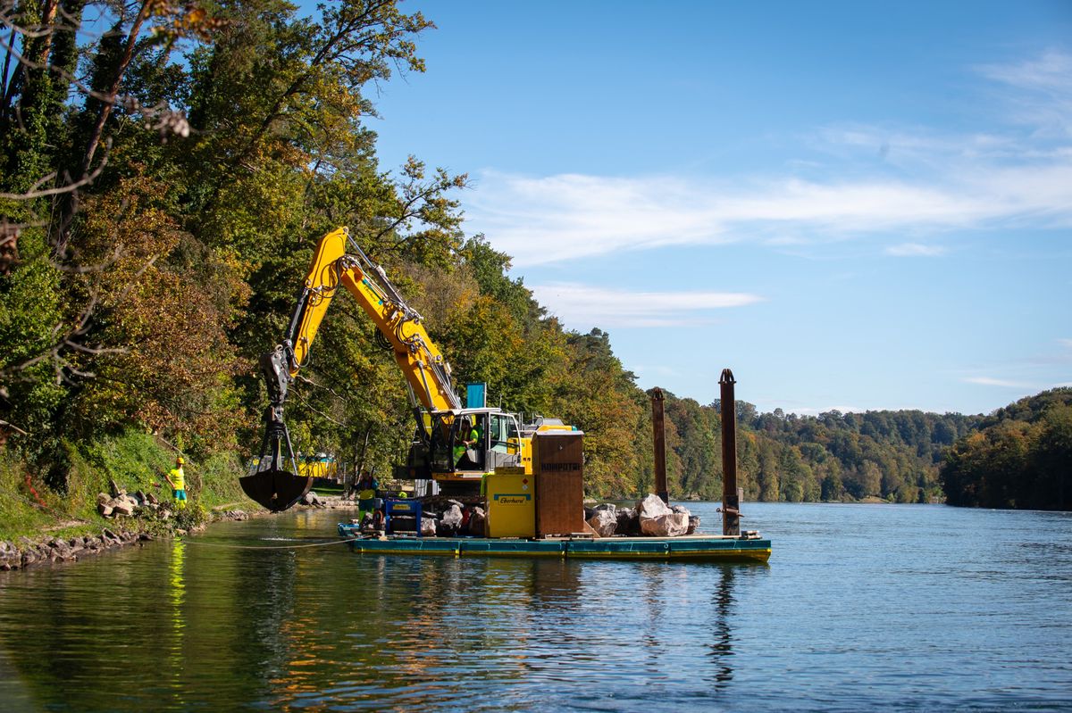 Bagger auf schwimmender Plattform flickt Wanderweg